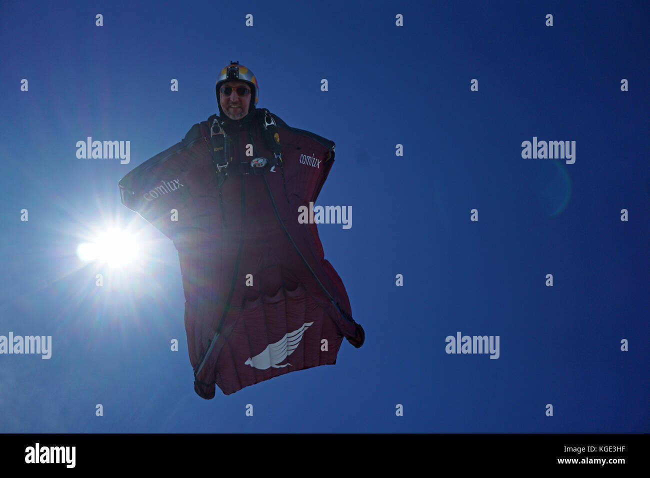 Wingsuit pilot is flying high in the sky over the Alps. Thereby the ...