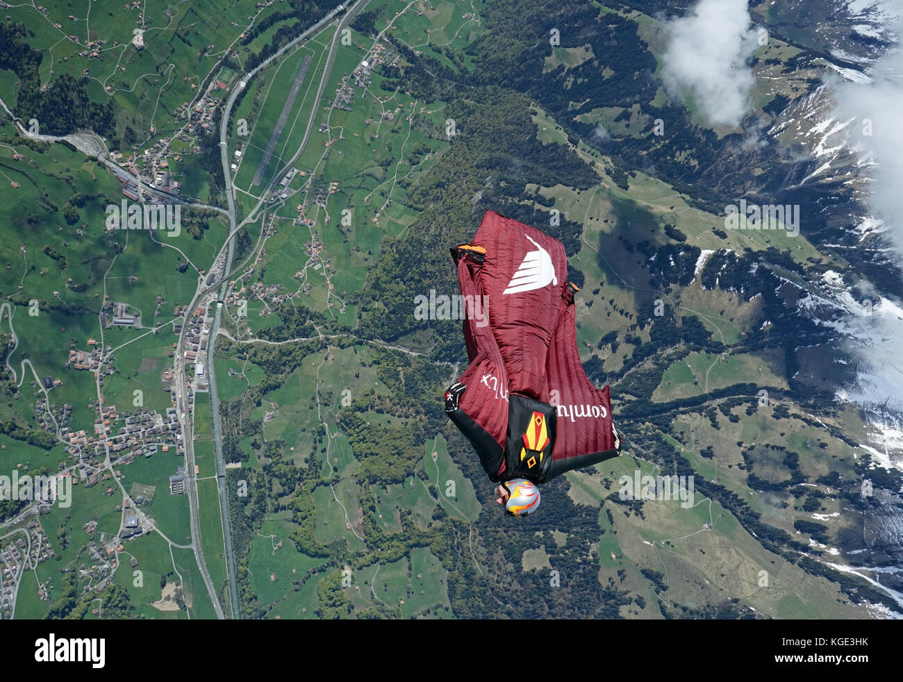 Wingsuit pilot is flying high in the sky over the Alps. Thereby the ...