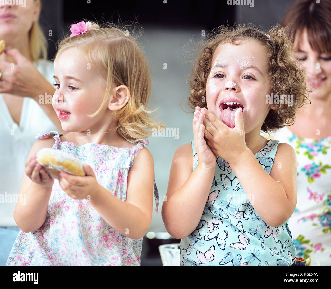 Two cute girls eating sweet, tasty doughnuts Stock Photo - Alamy