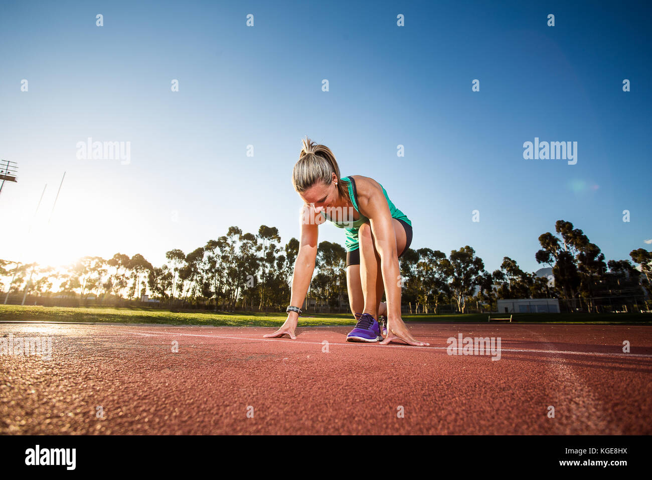 Close up wide angle view of a female sprinter athlete getting ready to ...