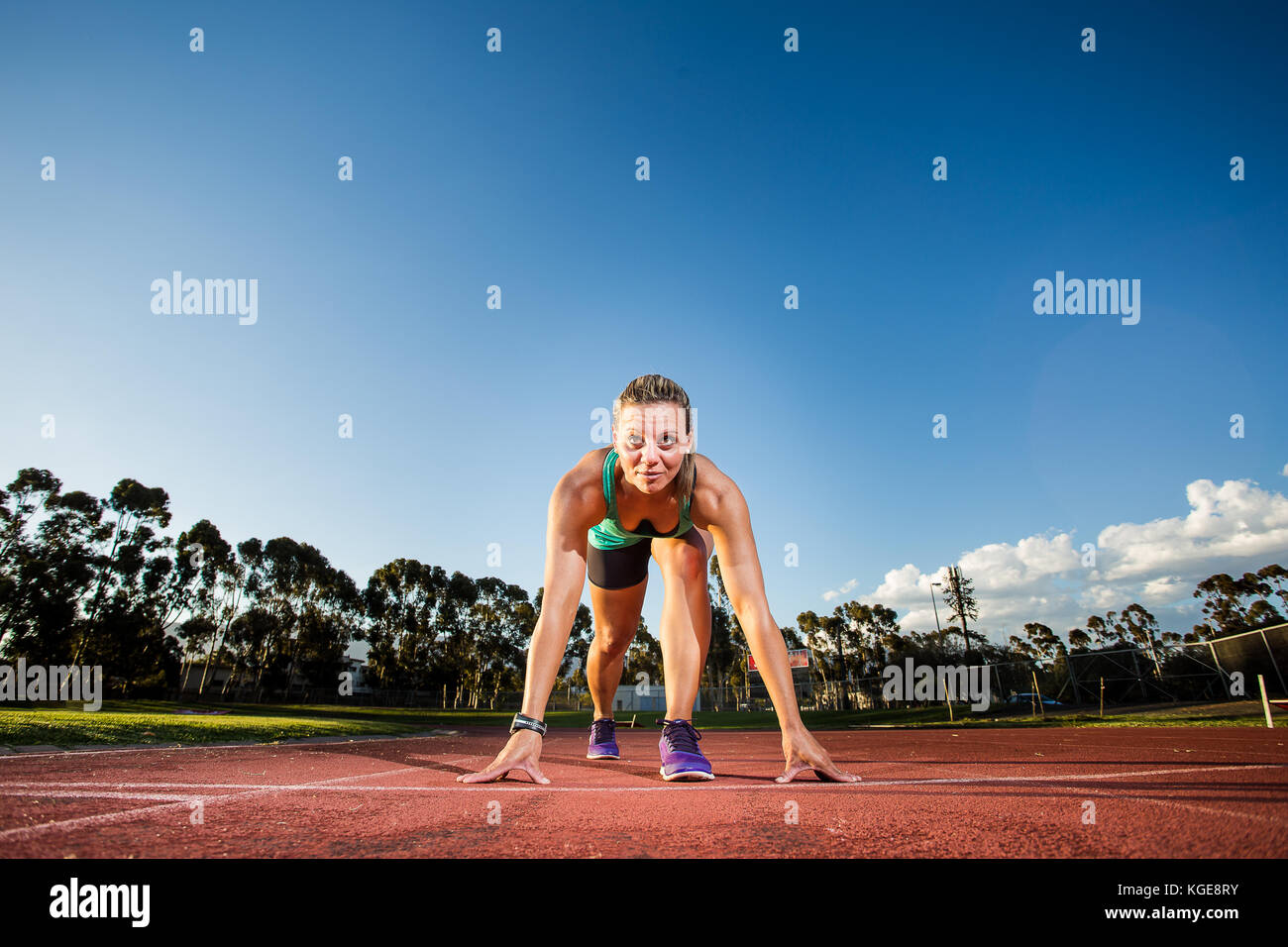 Close up wide angle view of a female sprinter athlete getting ready to ...