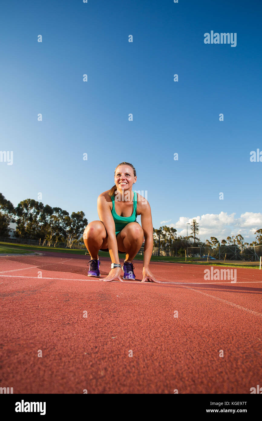Close up wide angle view of a female sprinter athlete getting ready to ...