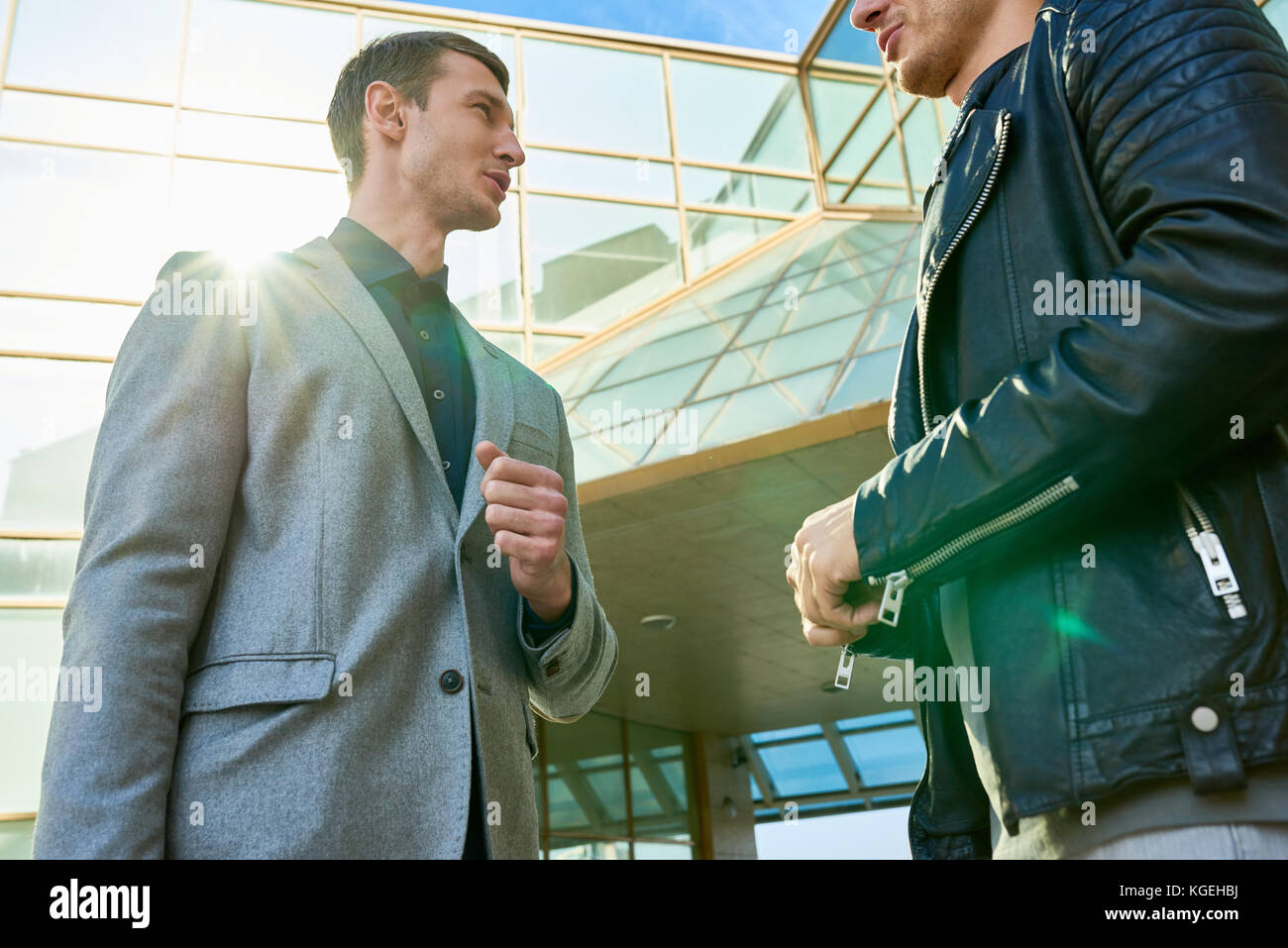 Low angle portrait of two handsome successful men talking outdoors ...