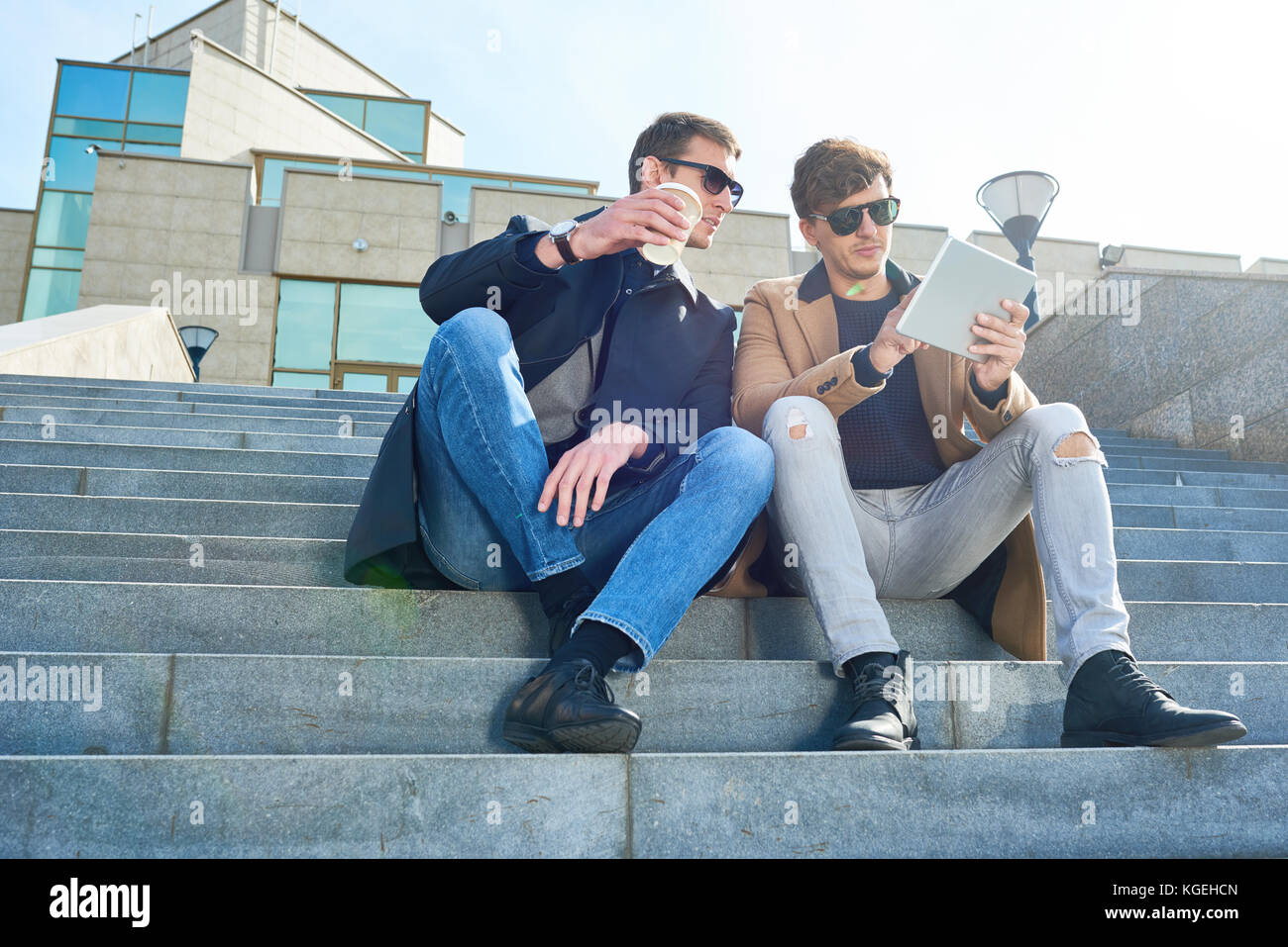 Portrait of two handsome young men using digital tablet outdoors ...
