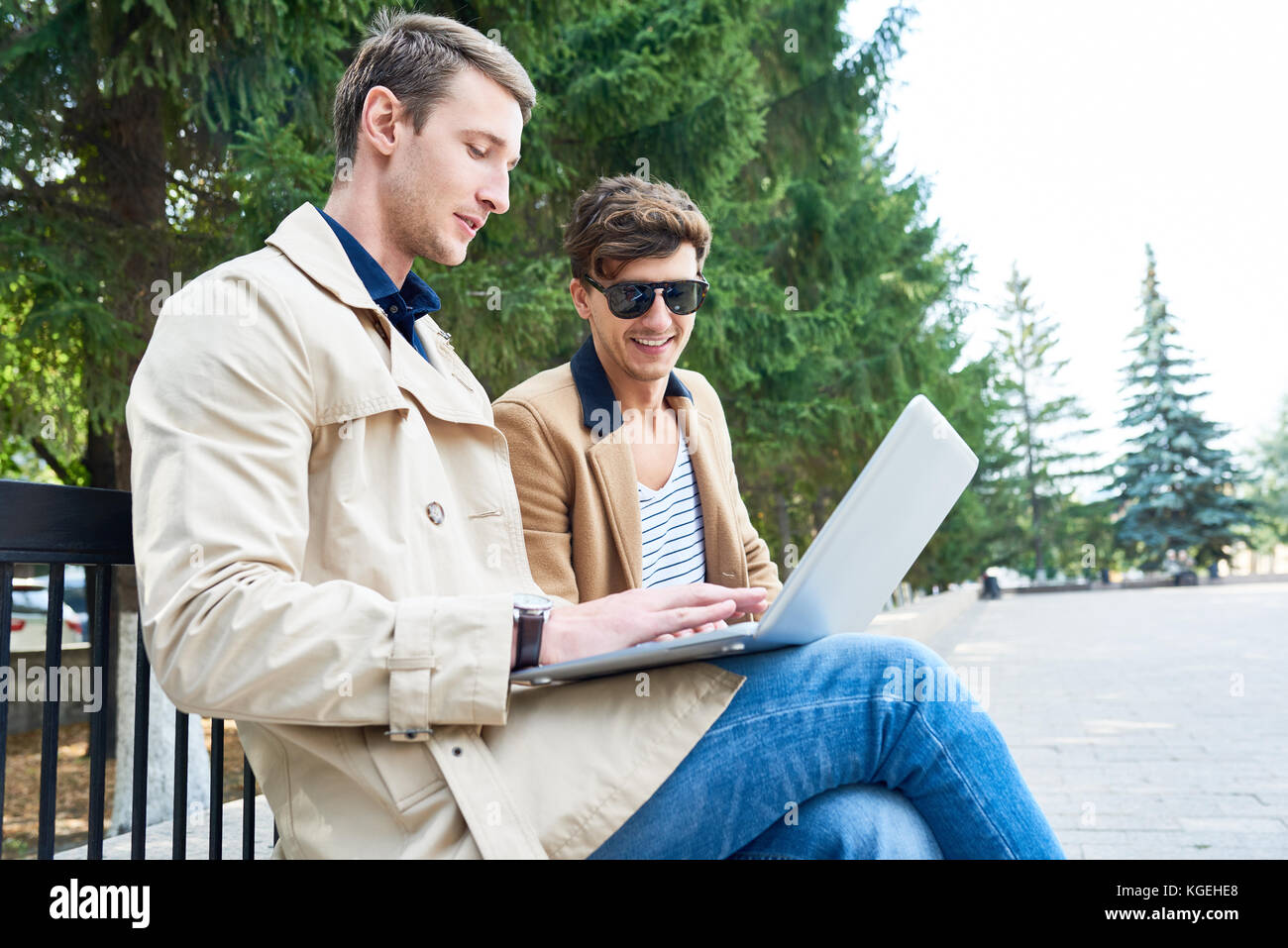 Side view portrait of two modern young men using laptop outdoors ...
