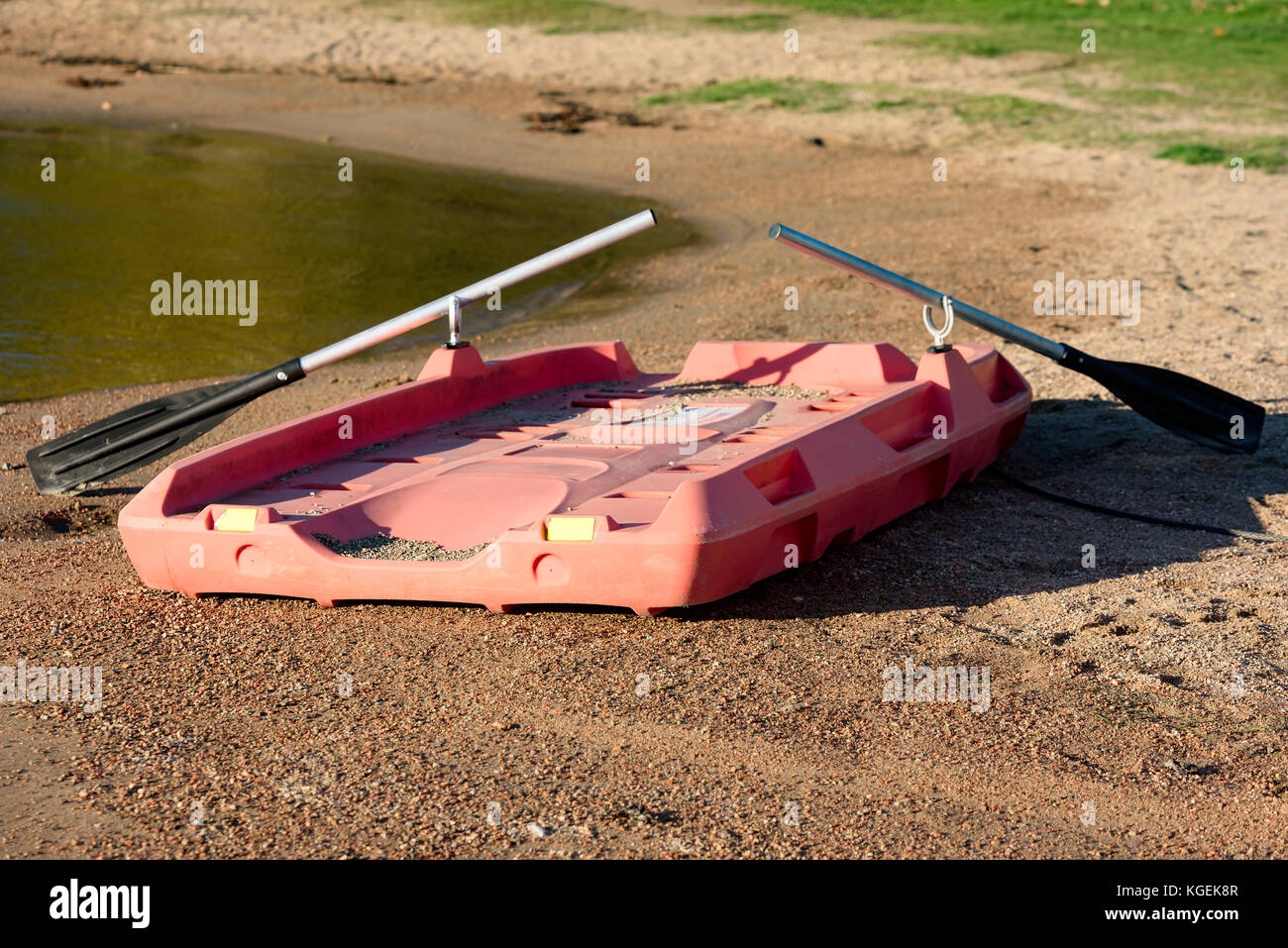 Life-saving equipment on beach. Orange plastic boat or raft with oars ...