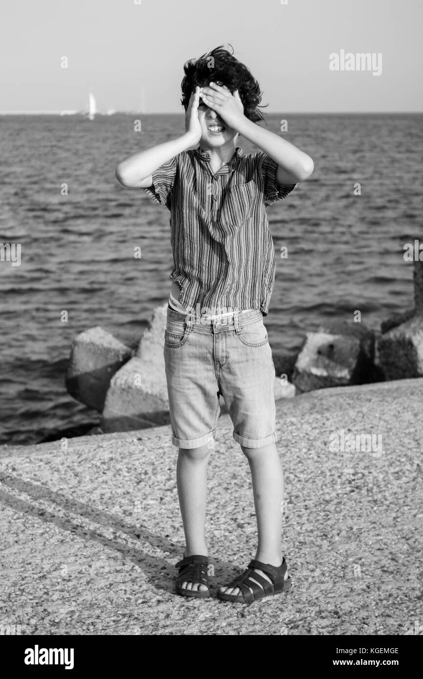 A disgruntled boy is standing by the sea. Black and white Stock Photo ...