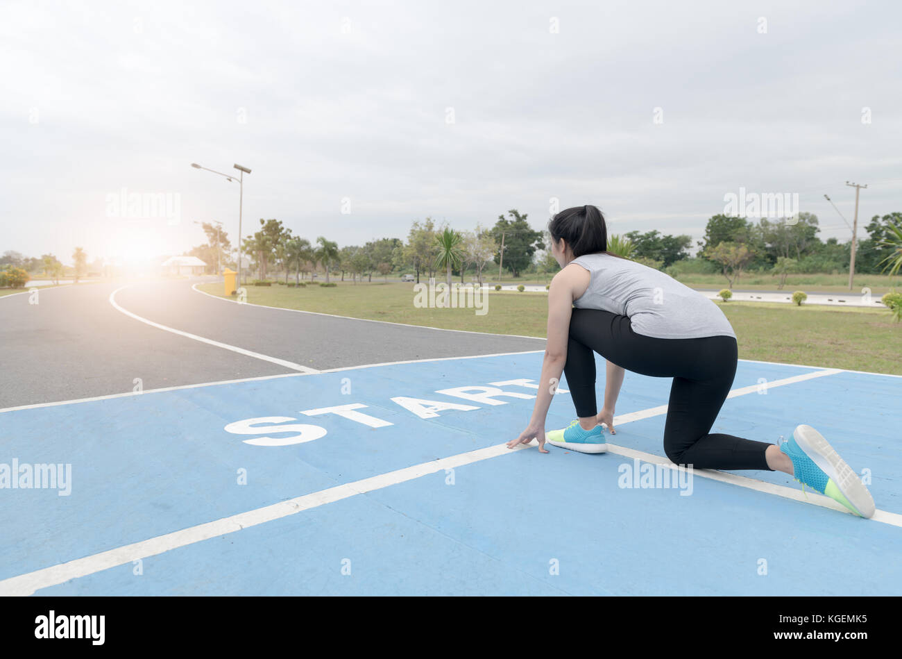 Fitness woman runner in start position at health park on morning ...