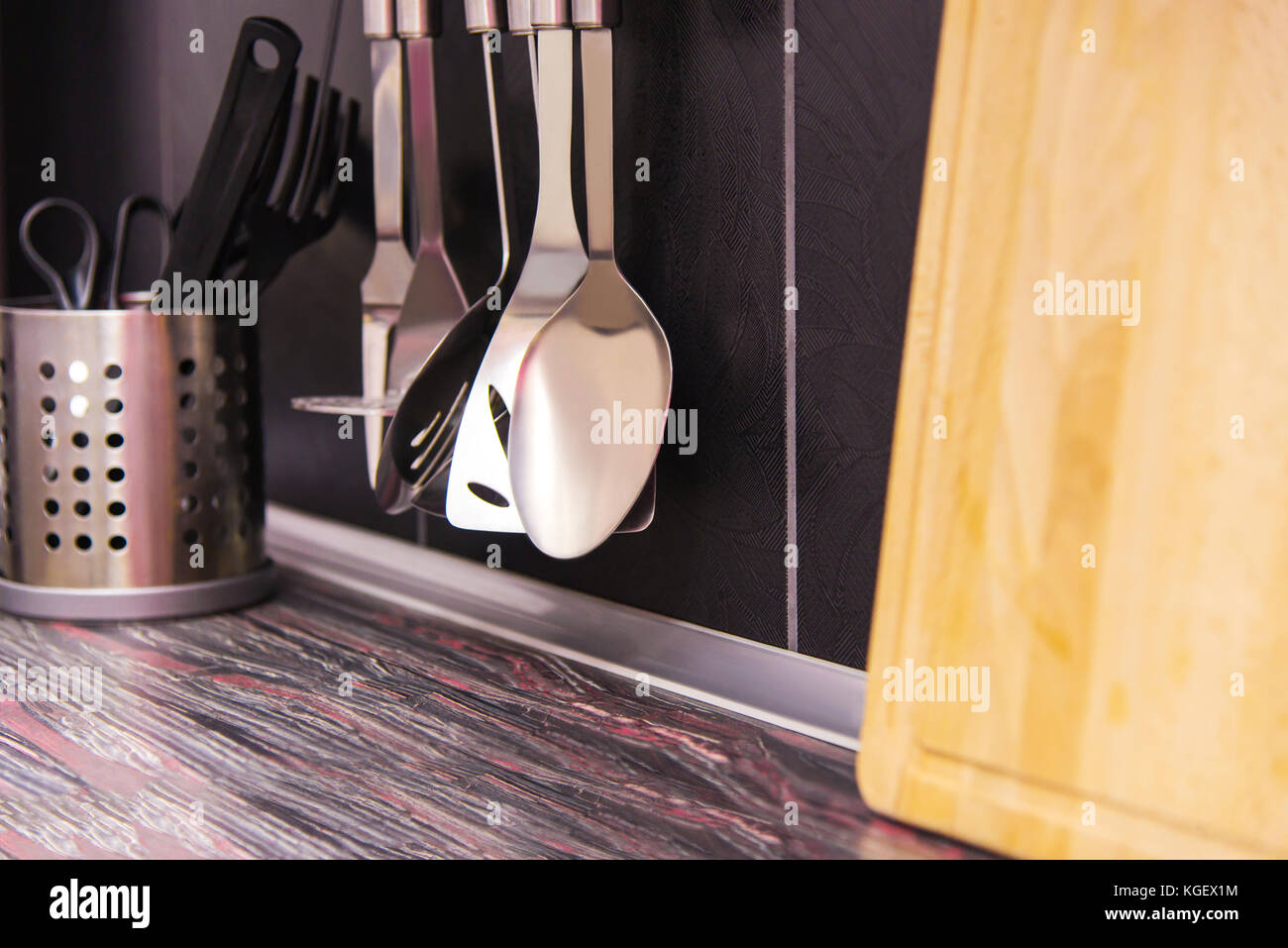 Black kitchen with kitchen hanging accessories on a tile background ...