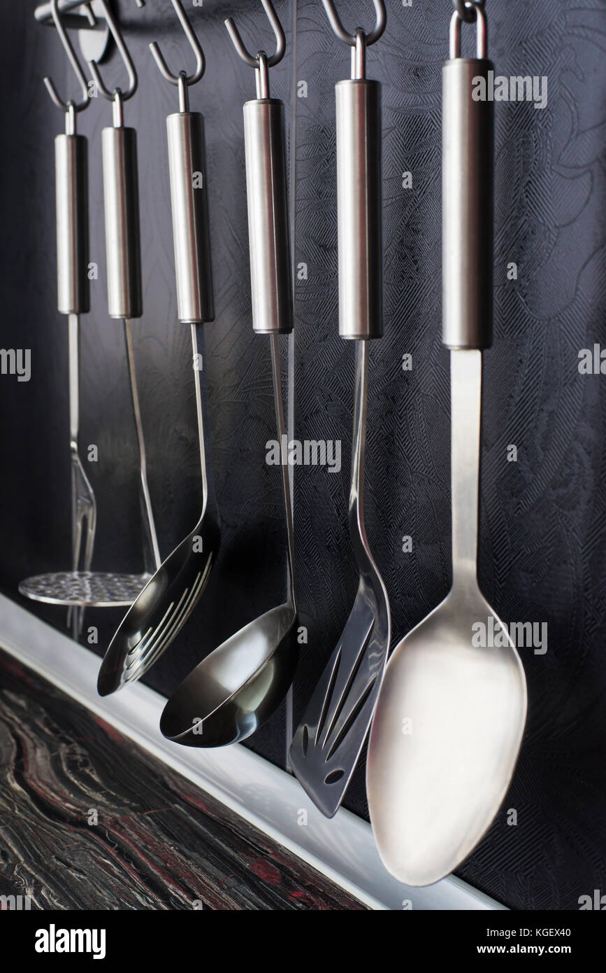 Black kitchen with kitchen hanging accessories on a tile background ...