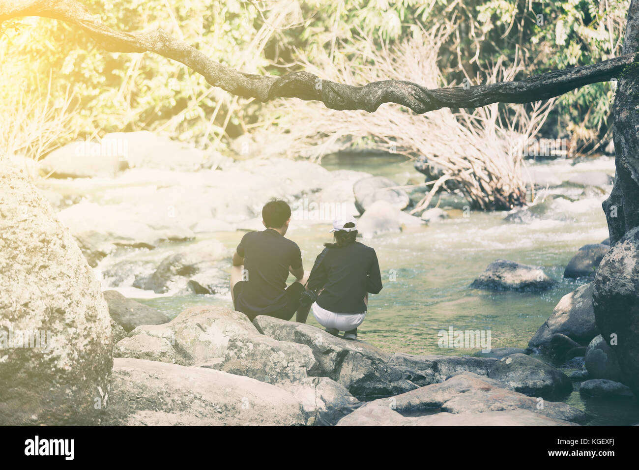 couple sitting together at the waterfall with happiness and romance ...