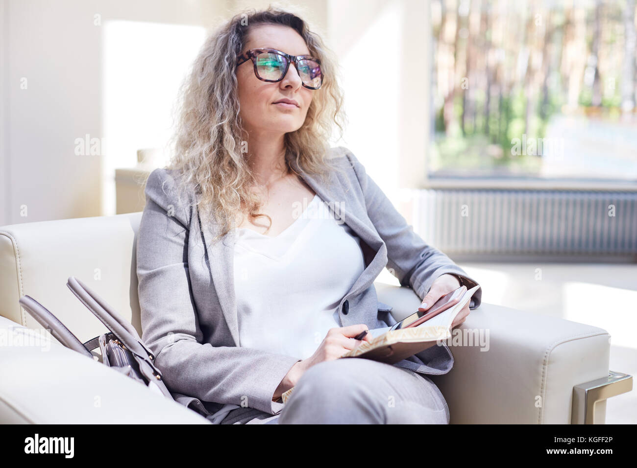Portrait shot of attractive middle-aged manager in eyeglasses looking ...