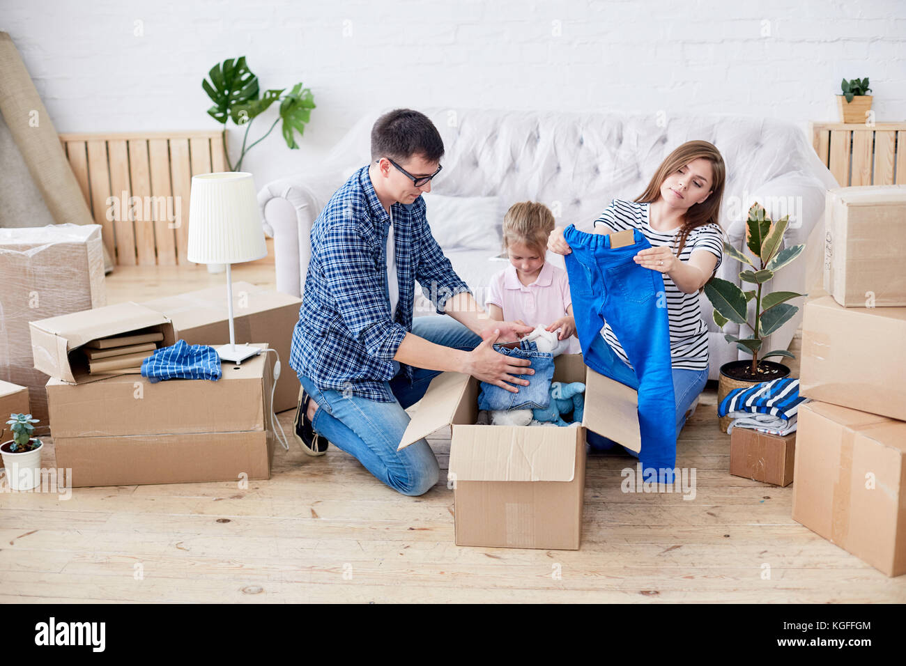 Adorable young family wrapped up in unpacking moving boxes while ...