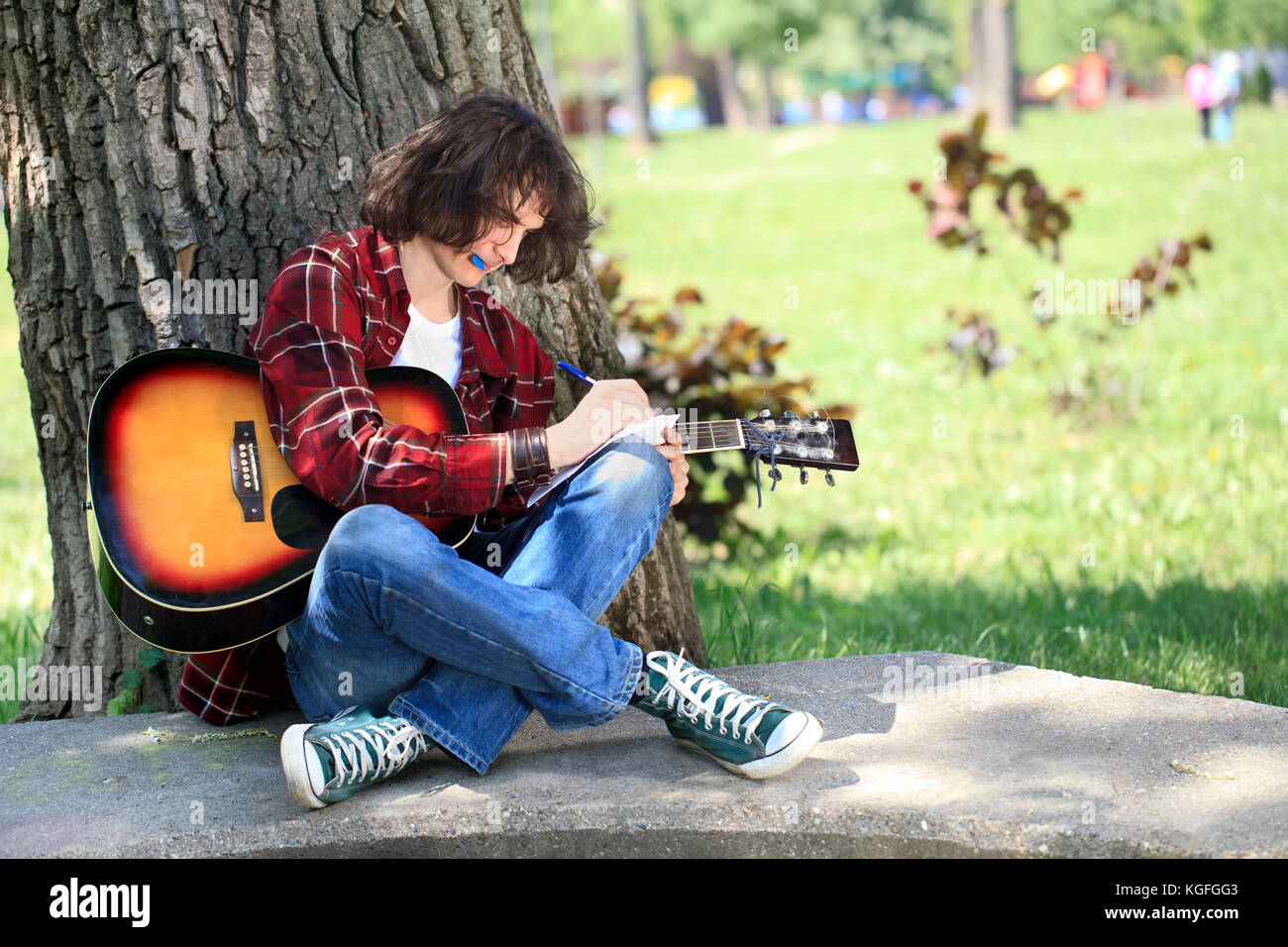 Young man composing for acoustic guitar in park Stock Photo - Alamy