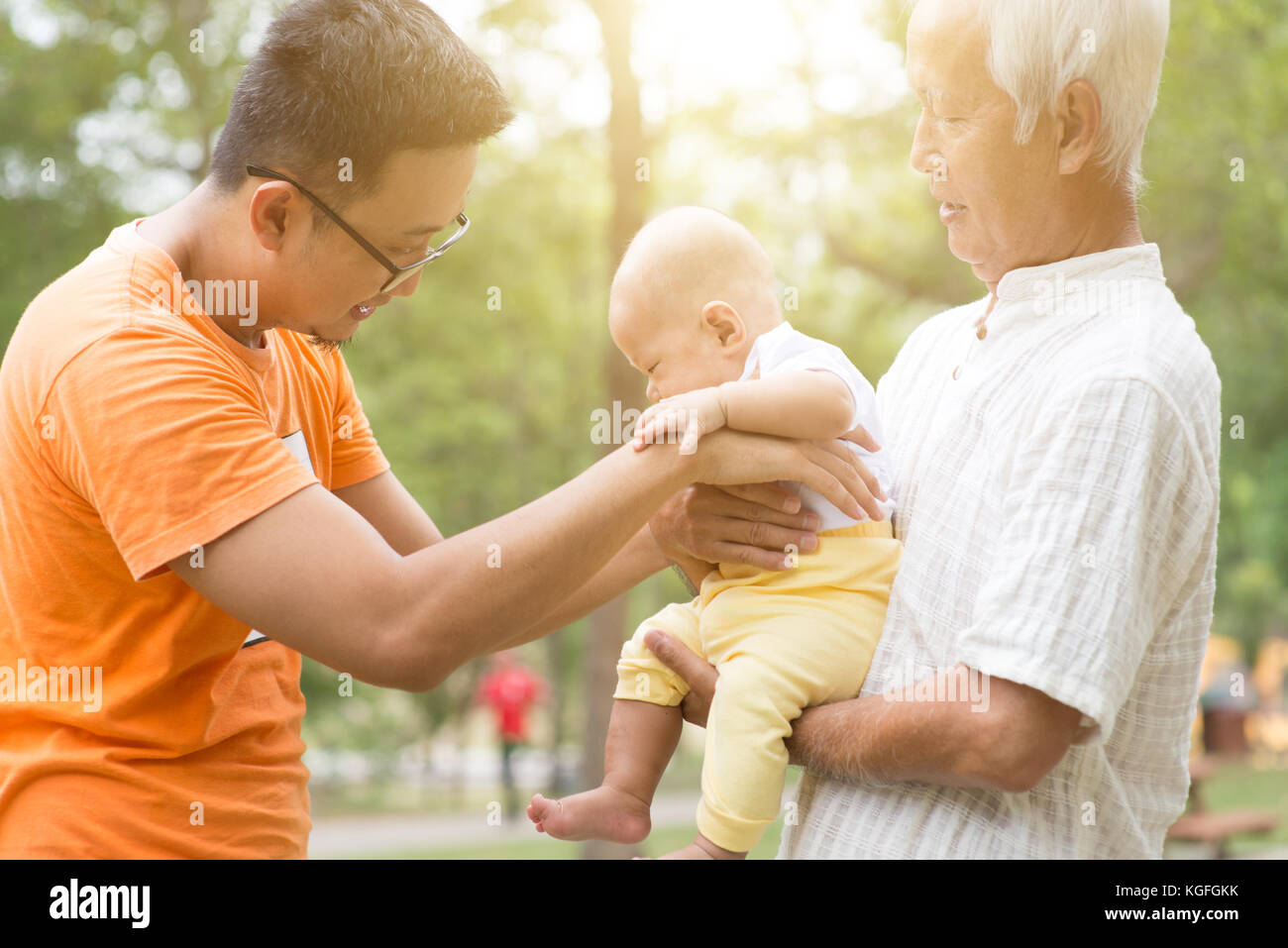 Grandfather and father taking care of baby grandson at outdoor park ...