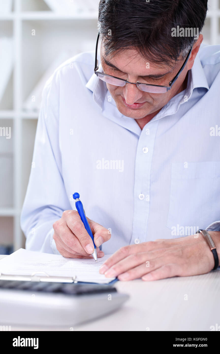 Business man sitting in office with laptop writing note Stock Photo - Alamy
