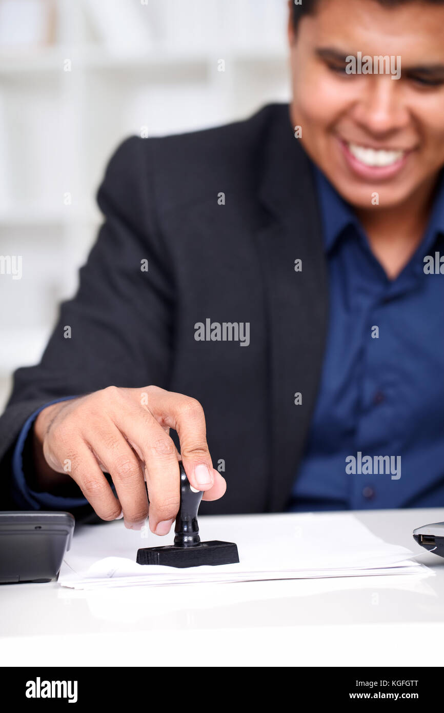 Young businessman at his desk stamping document Stock Photo - Alamy