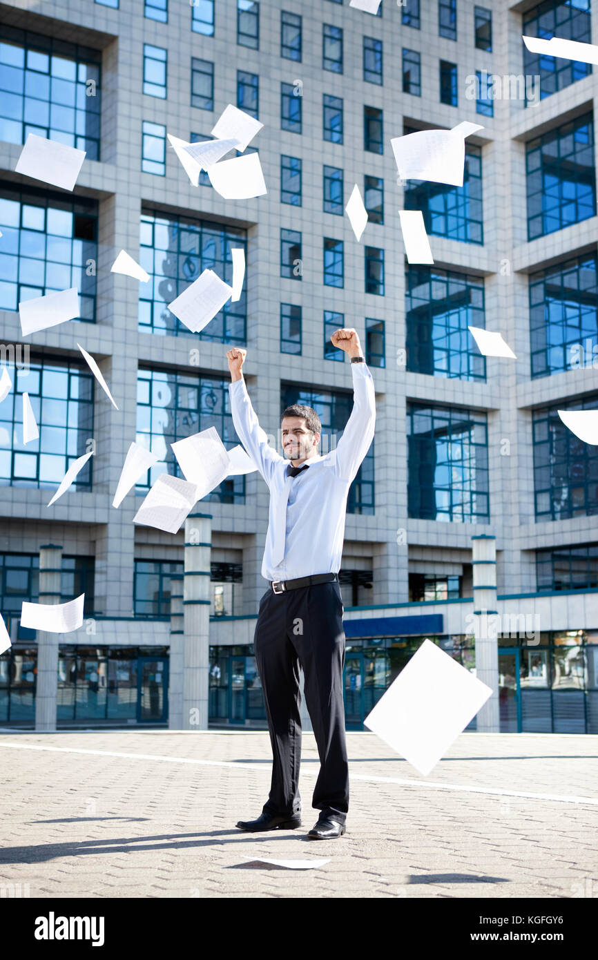 Businessman throwing paperwork in air against office building Stock ...