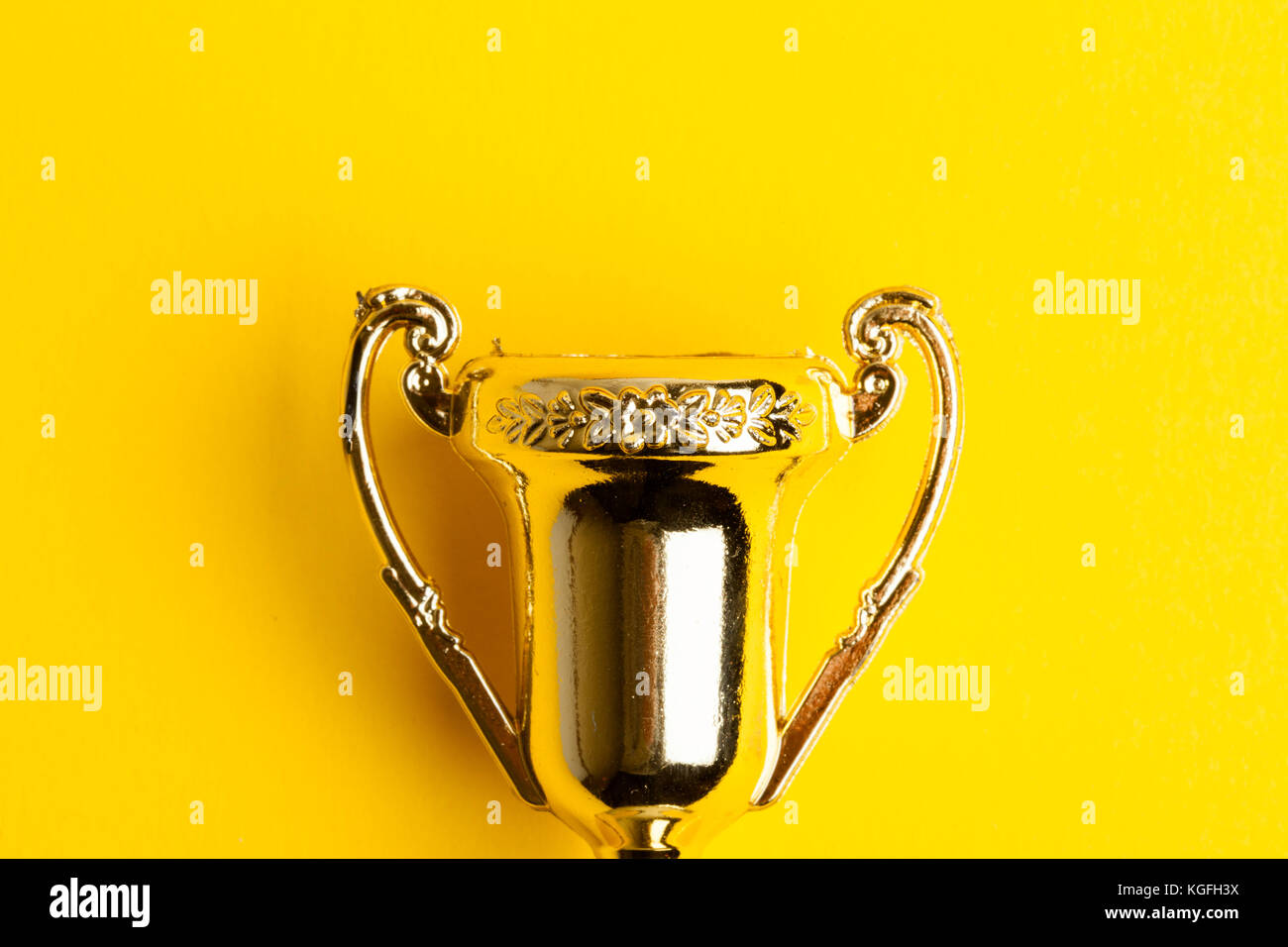 Gold winners achievement trophy on a yellow background Stock Photo - Alamy