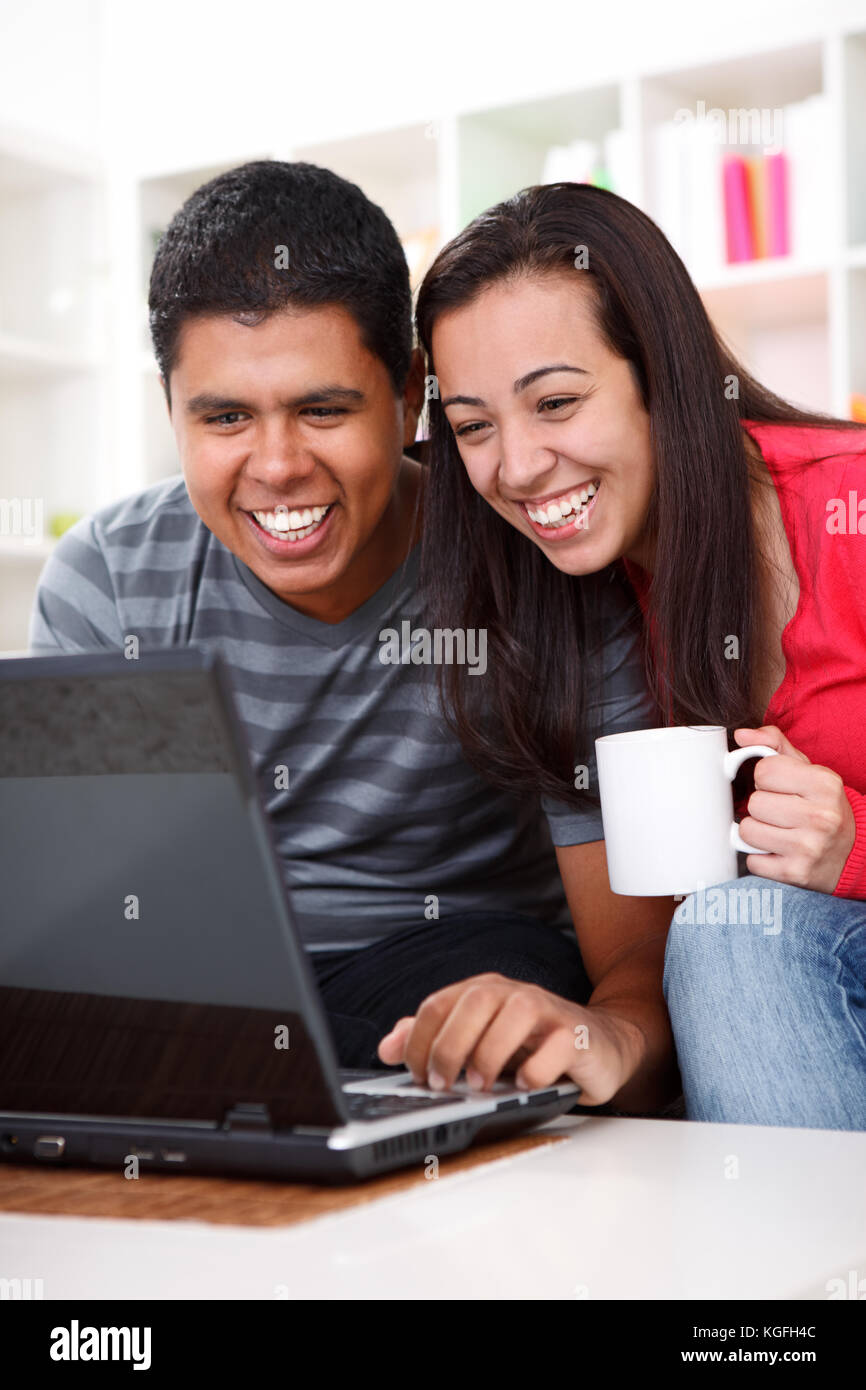 Laughing young couple looking at laptop in home Stock Photo - Alamy