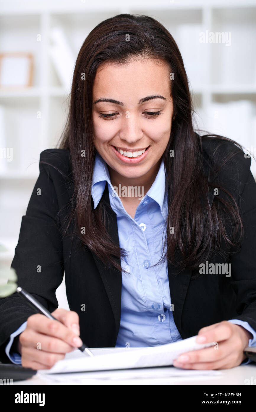 young businesswoman making note, sitting on desk in office Stock Photo ...