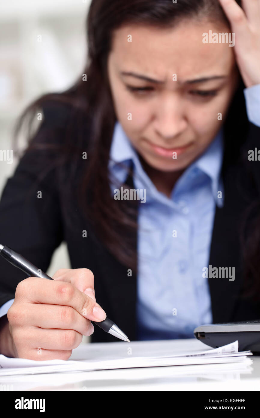 Worried businesswoman making note and holding head Stock Photo - Alamy