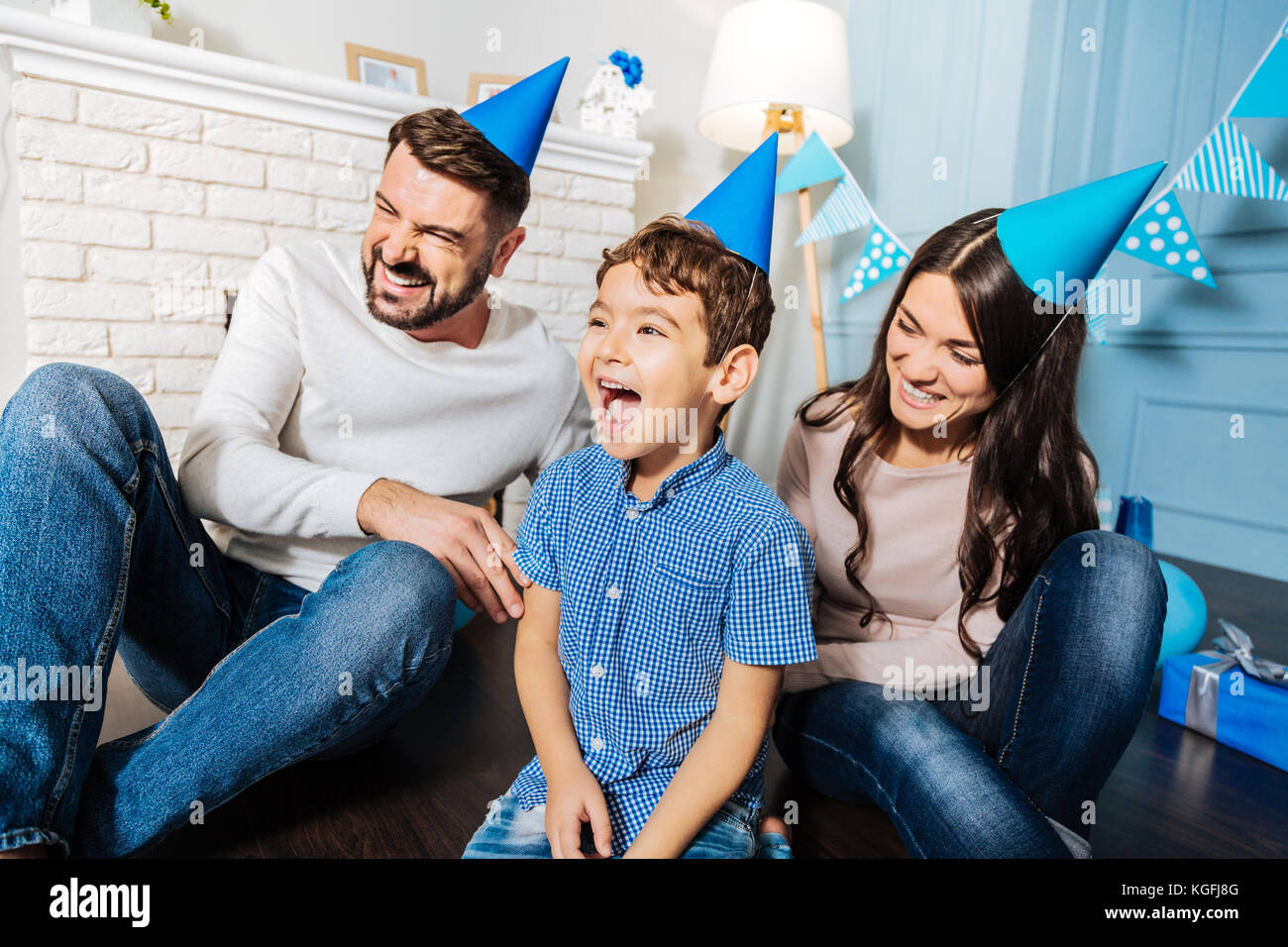 Upbeat family in party hats laughing together on the floor Stock Photo ...
