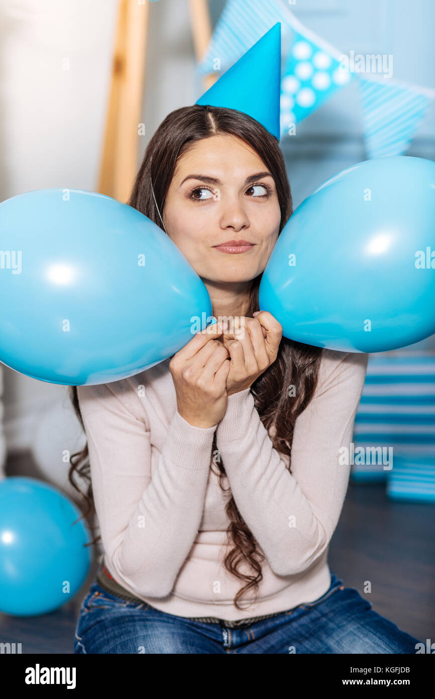 Cheerful woman holding two balloons near her cheeks Stock Photo - Alamy