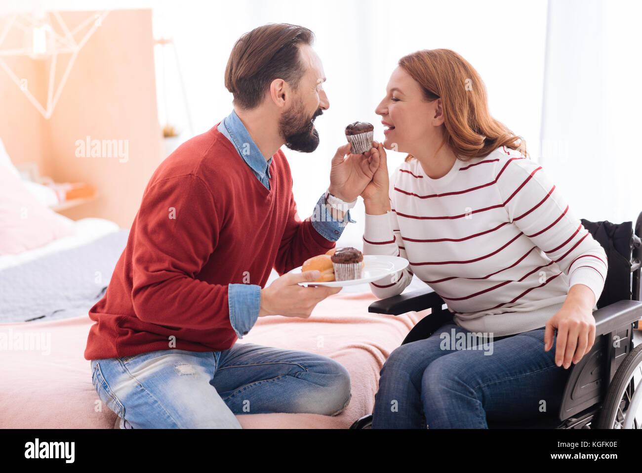 Joyful man and disabled woman eating cookies Stock Photo - Alamy
