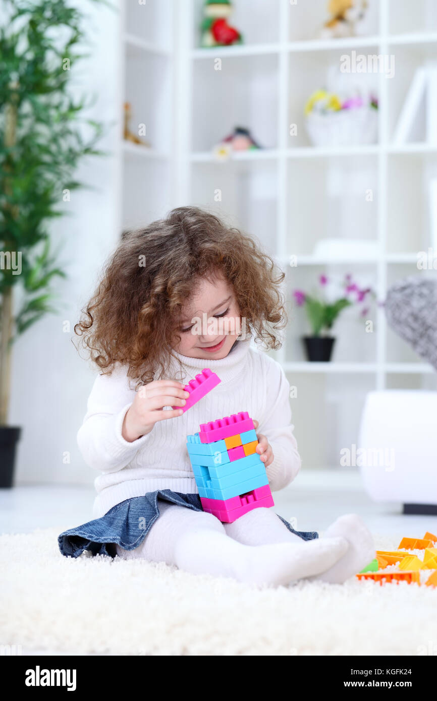 Smiling little girl playing with construction blocks Stock Photo - Alamy