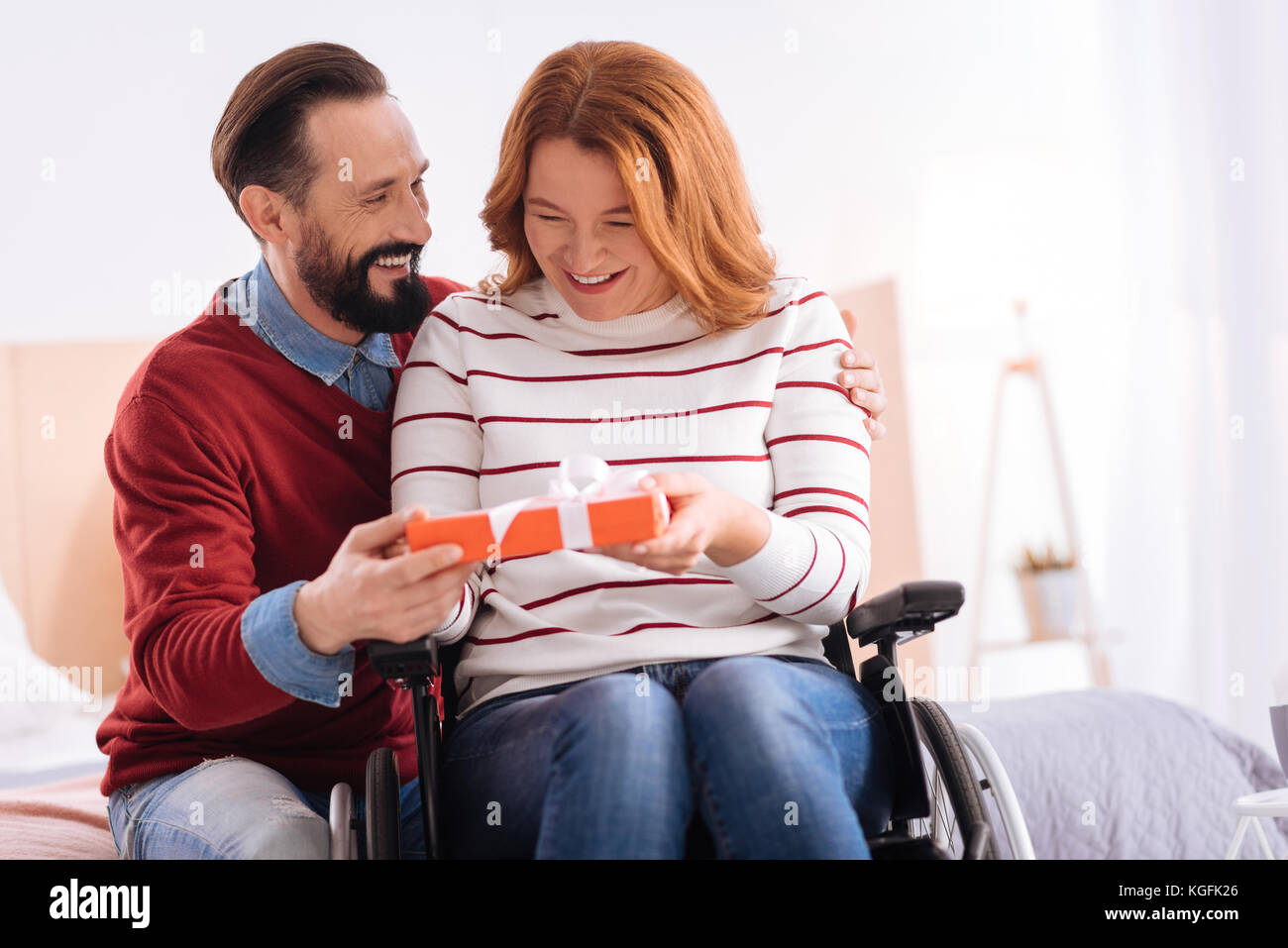 Smiling man giving a gift to a happy disabled woman Stock Photo - Alamy