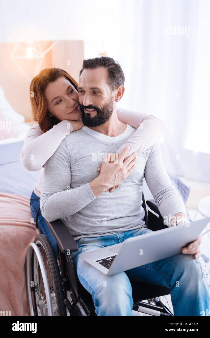 Cheerful woman and disabled man hugging and holding hands Stock Photo ...