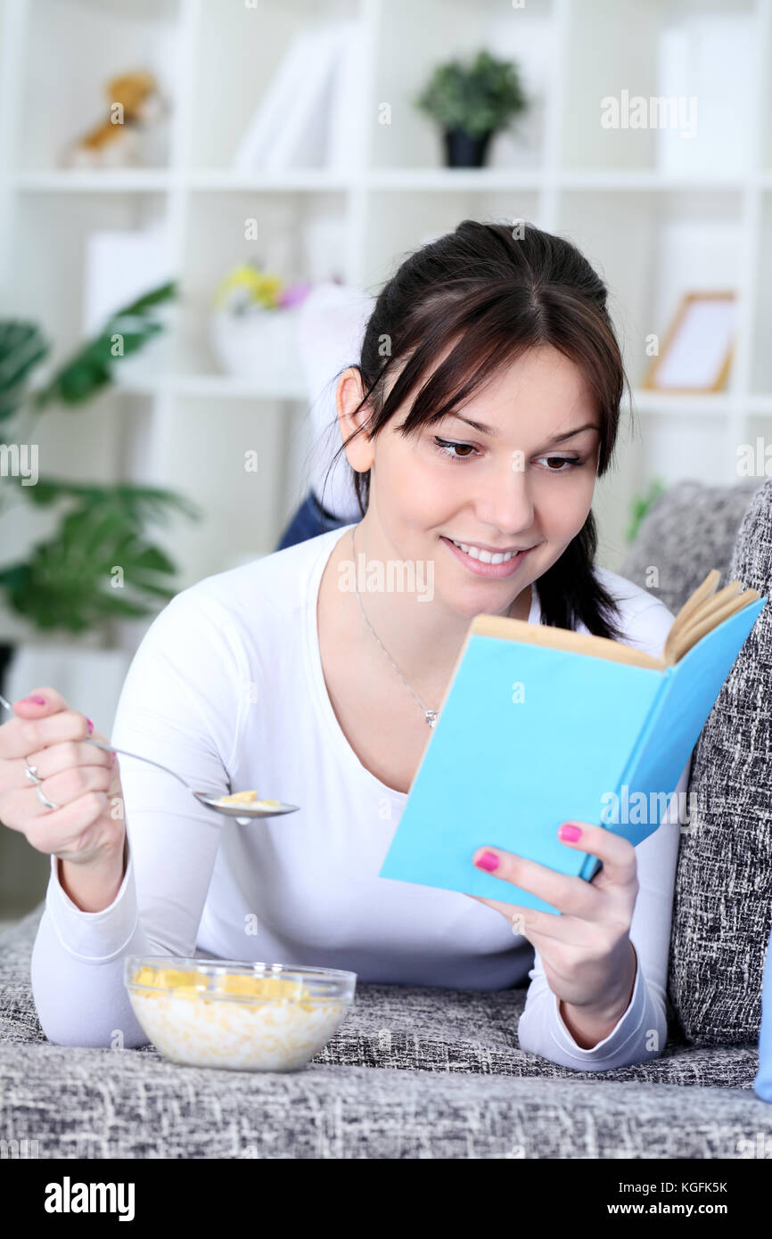 Young healthy woman reading book and eating snack Stock Photo - Alamy