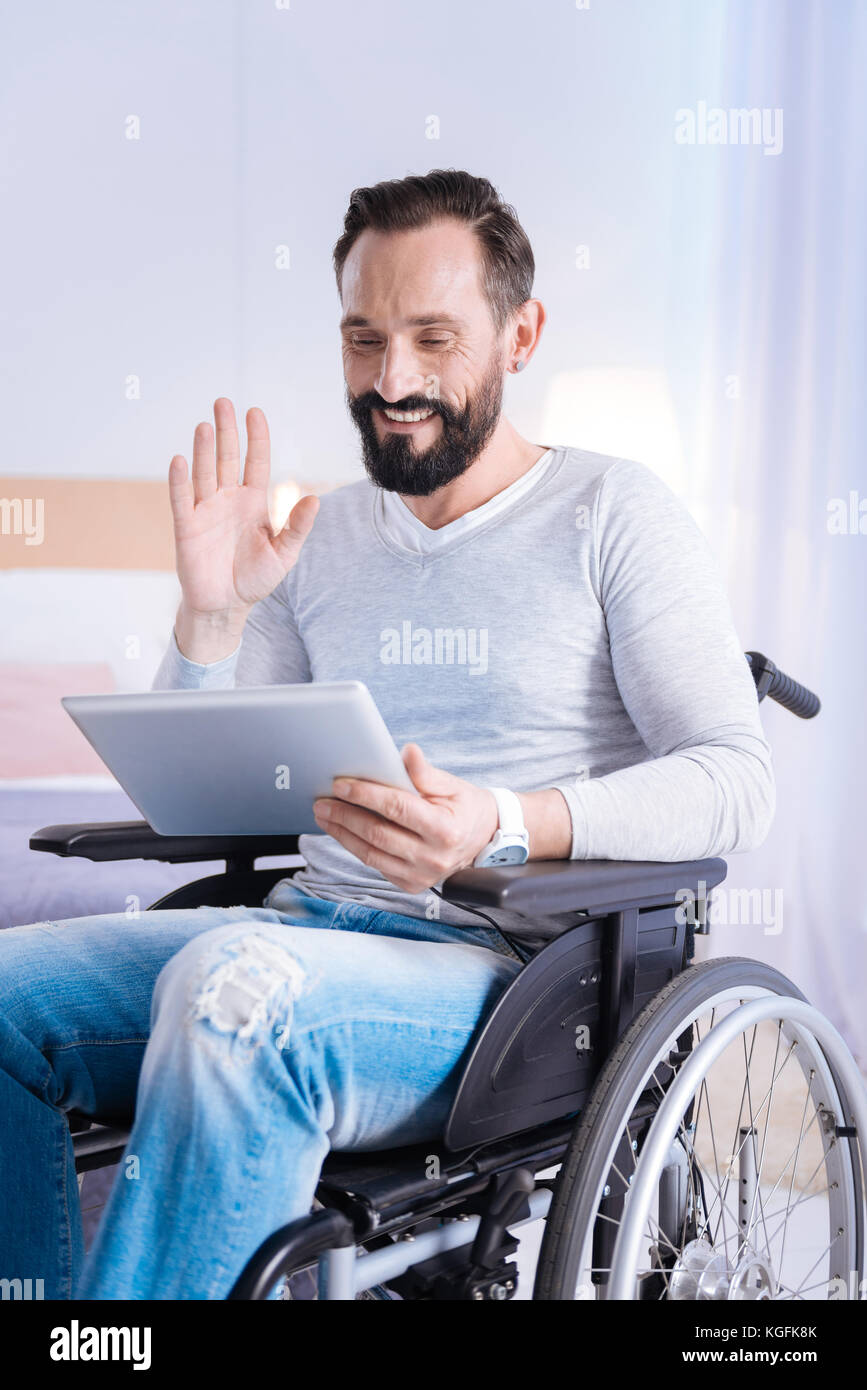 Joyful crippled man waving at the screen Stock Photo - Alamy