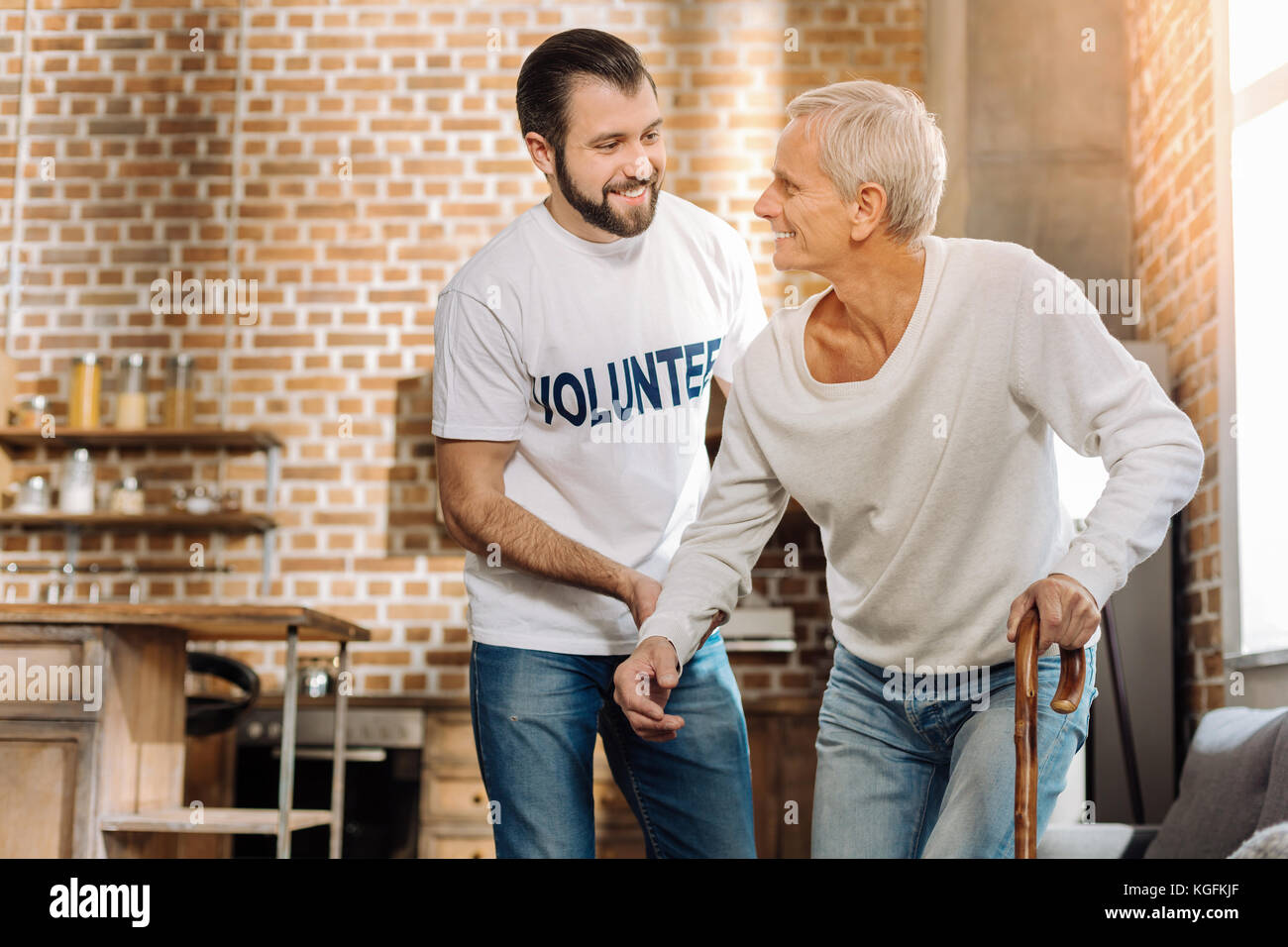 Helpful young volunteer supporting a senior person Stock Photo - Alamy