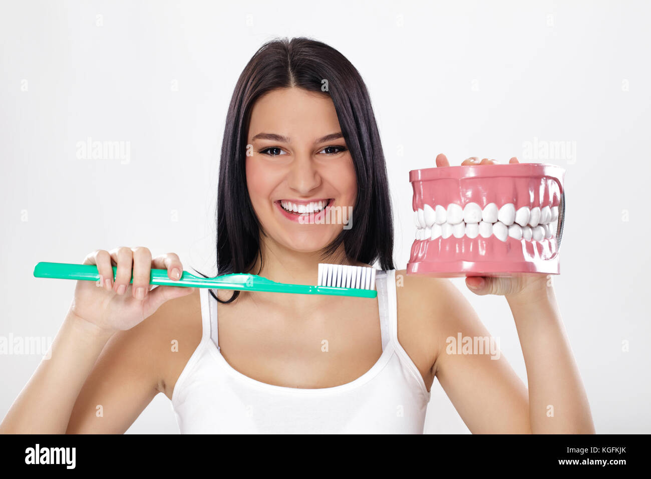 Smiling girl holding model of teeth and toothbrush Stock Photo - Alamy