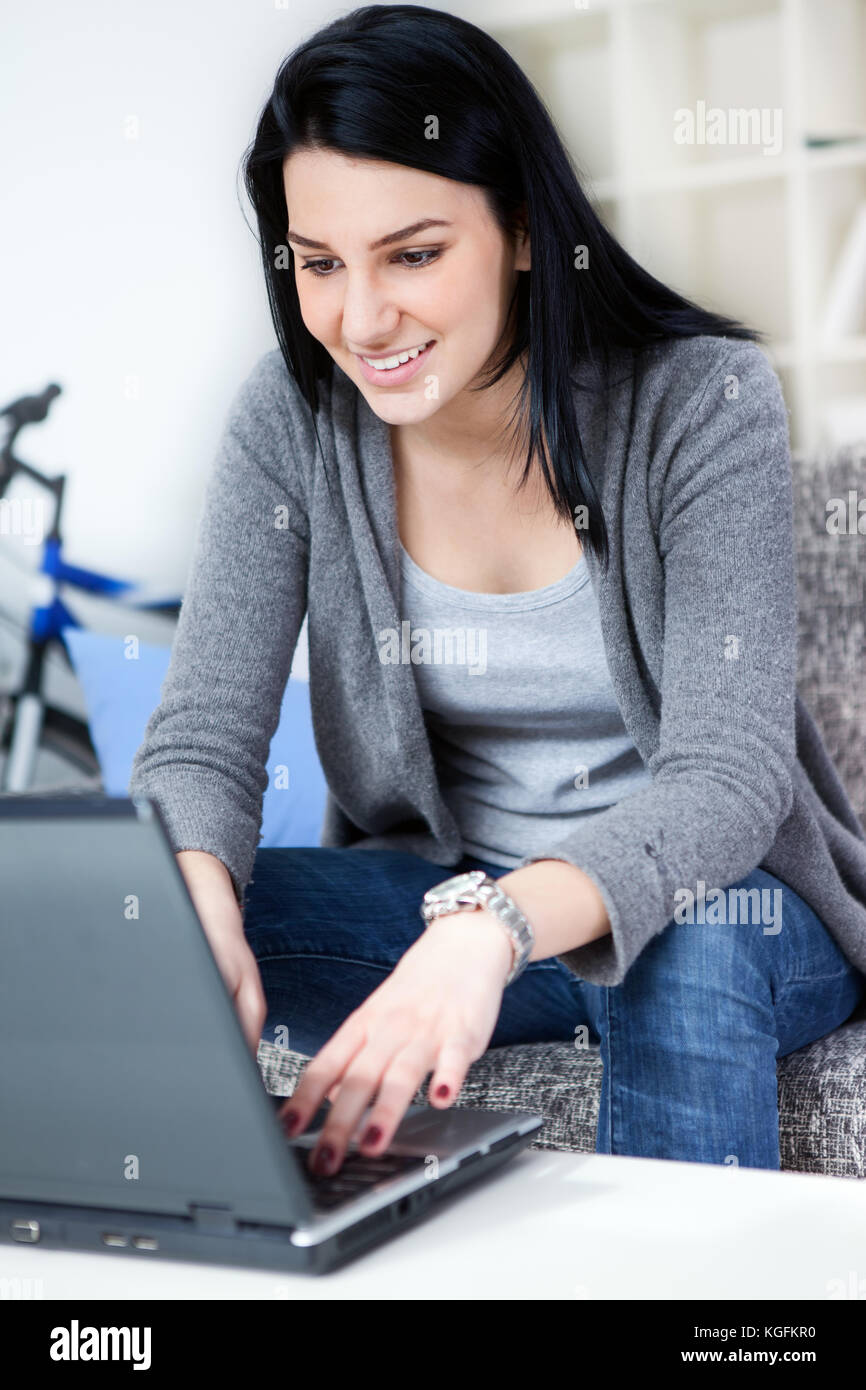 Portrait of a cheerful young woman smiling while using laptop Stock ...