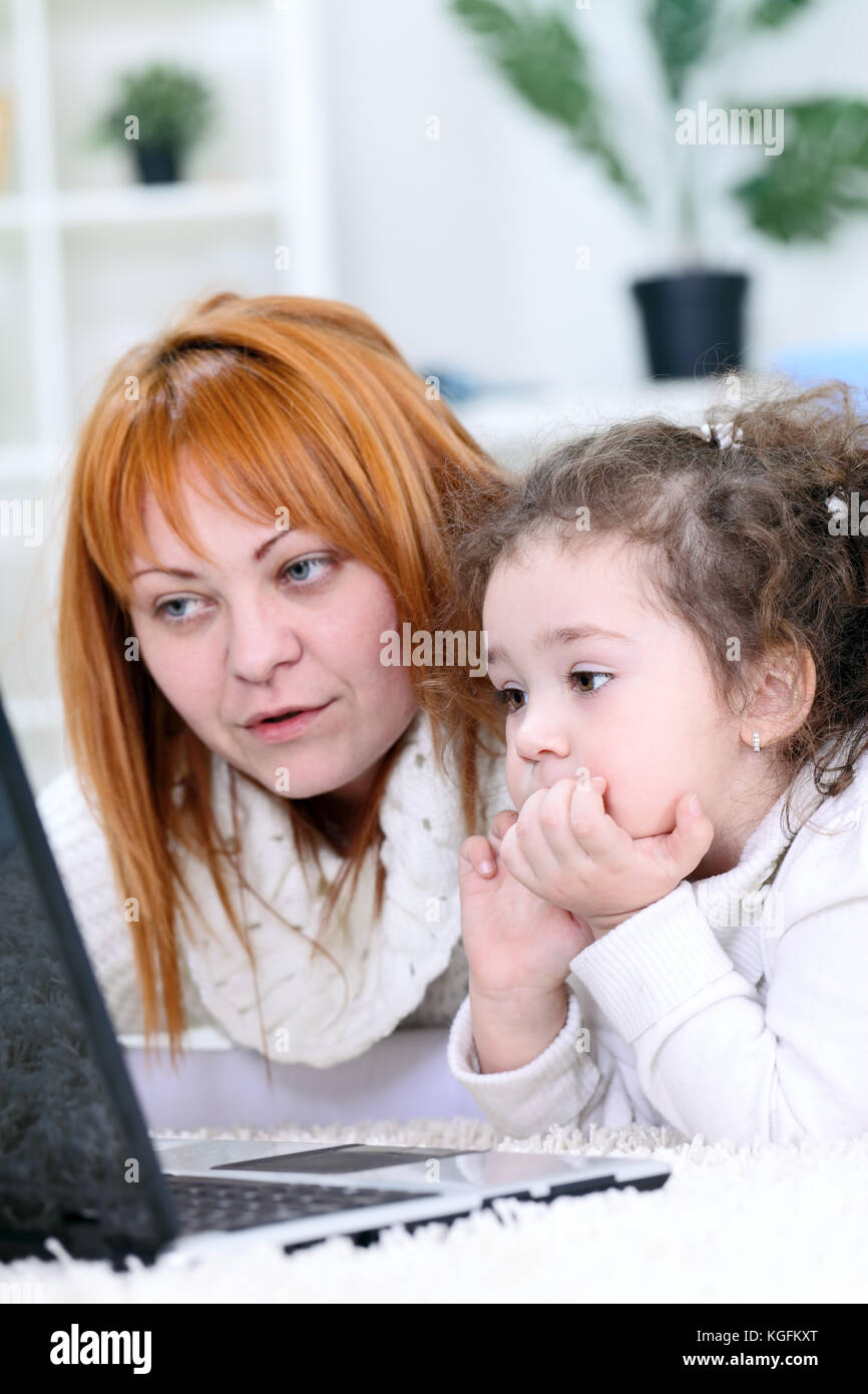 Young woman with daughter using laptop computer at home Stock Photo - Alamy