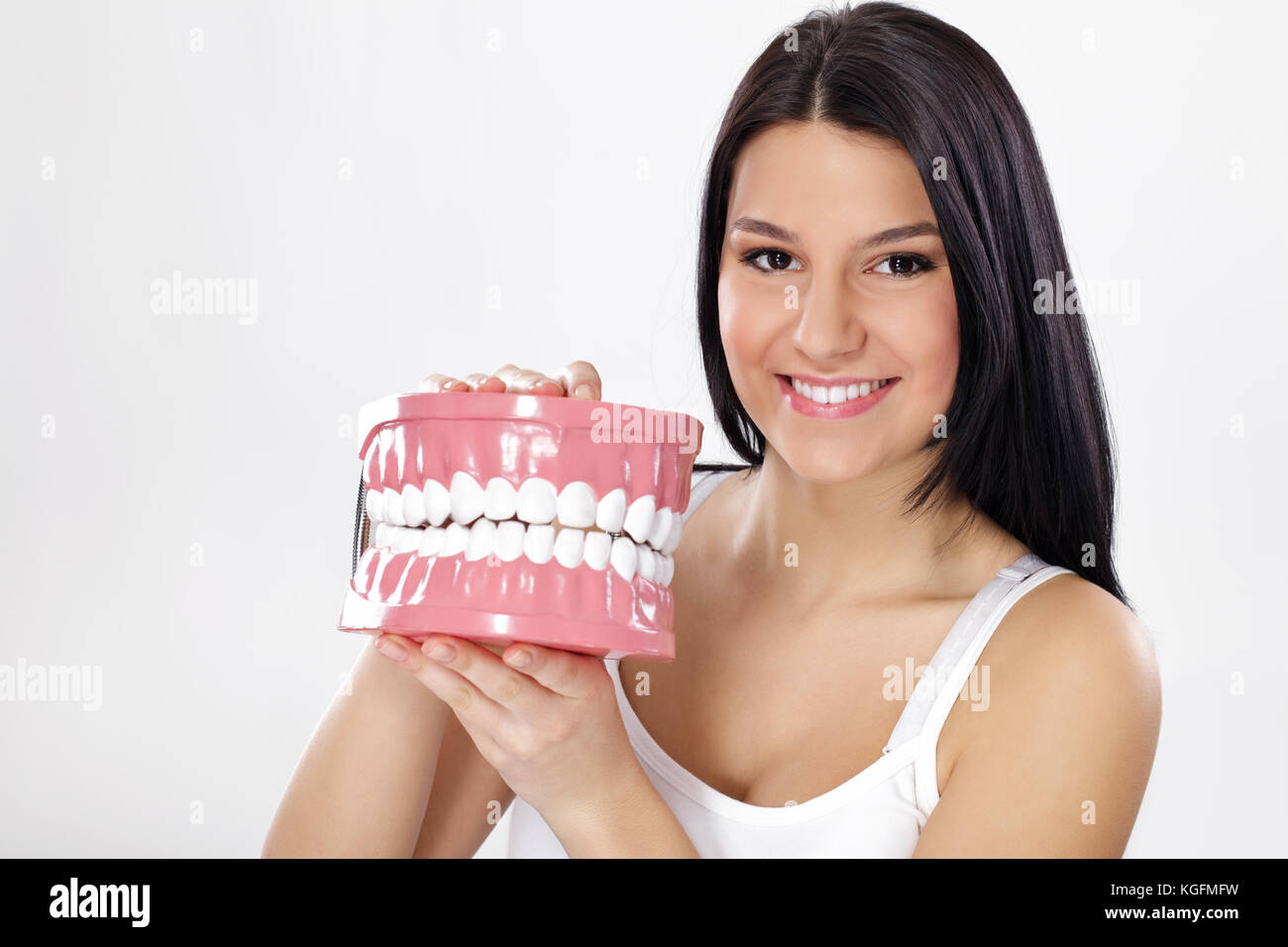 Smiling young woman holding plastic big model of jaws with teeth Stock ...