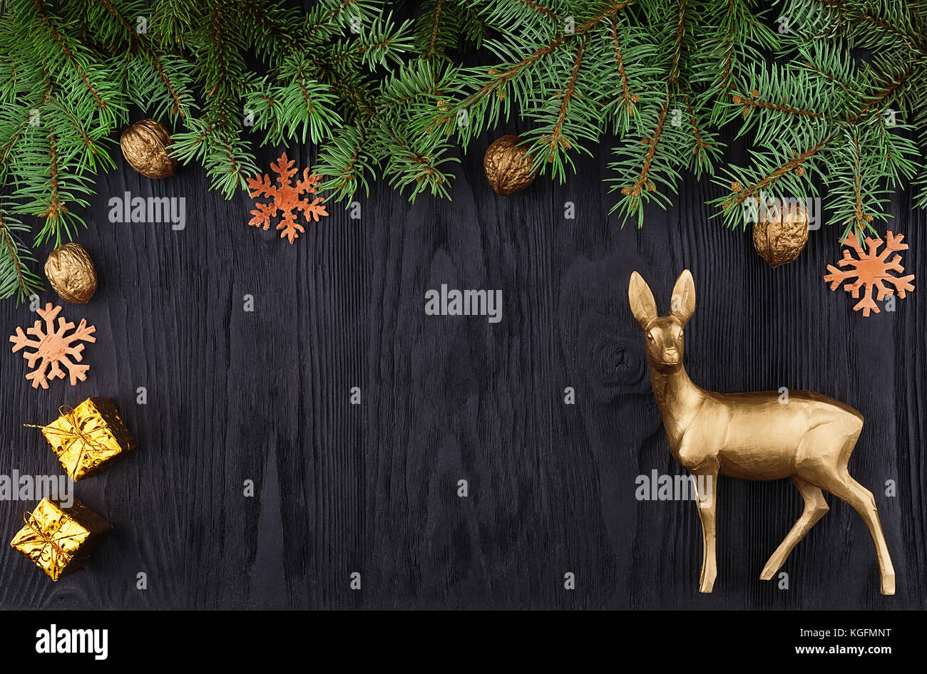 Christmas frame with spruce branches and a golden deer on a black ...