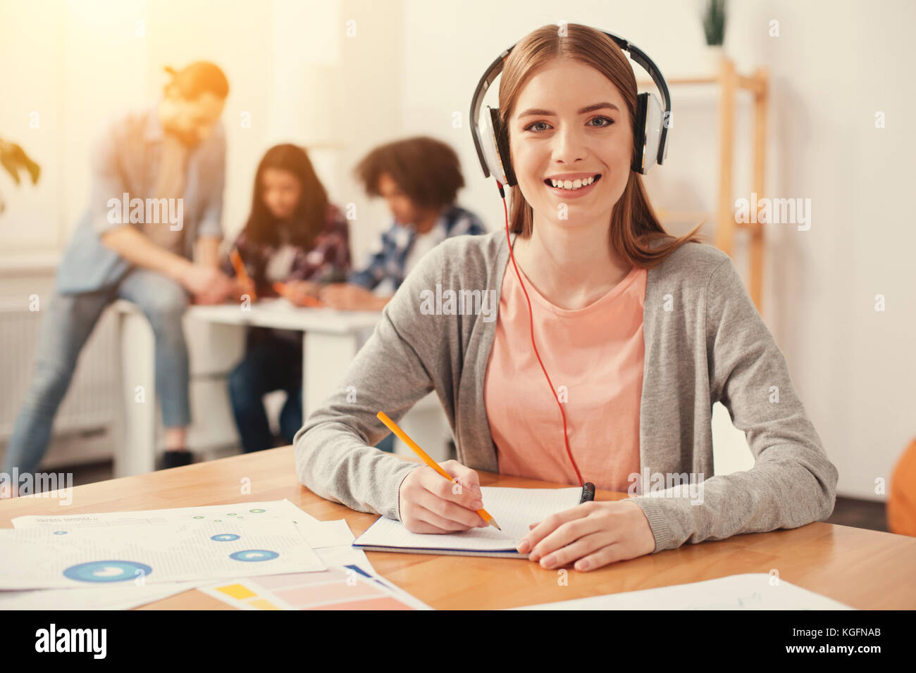 Longhaired woman smiling while writing in a notebook Stock Photo - Alamy