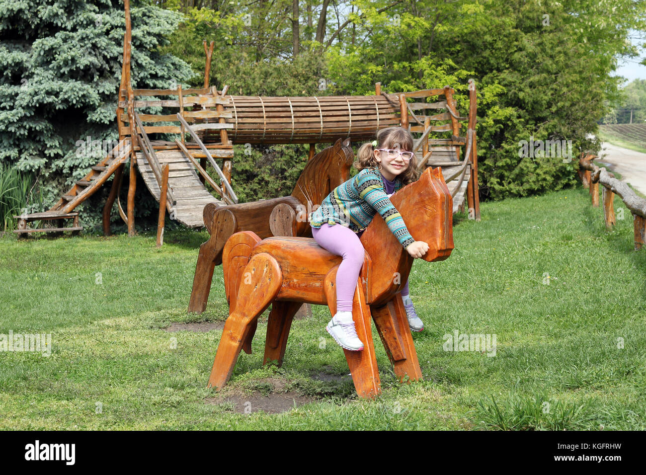 little girl riding wooden horse on playground Stock Photo - Alamy