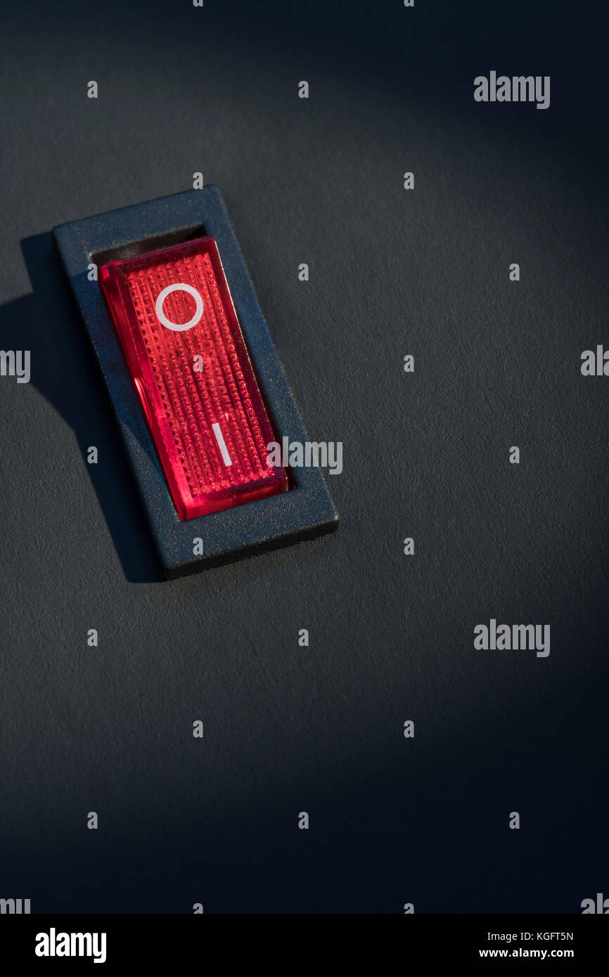 Illuminated red electrical switch on black background - potential ...