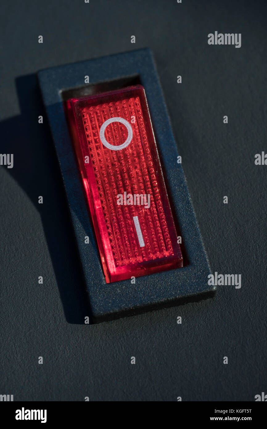 Illuminated red electrical switch on black background - potential ...