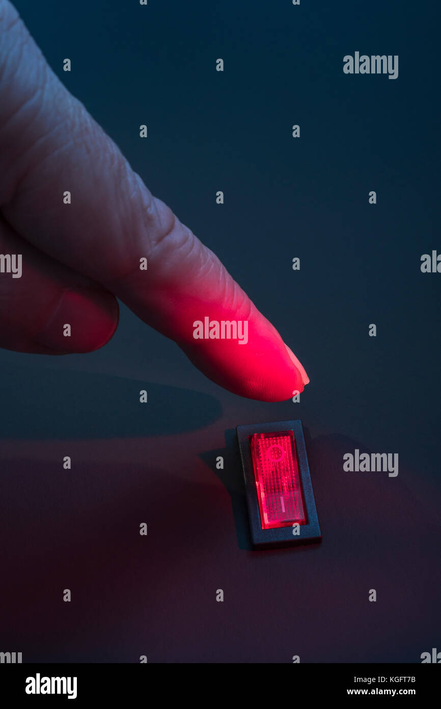 Finger hovering over illuminated red electrical switch - potential ...
