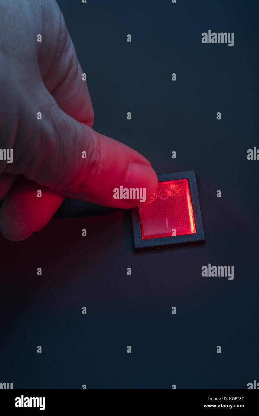 Finger hovering over illuminated red electrical switch - potential ...