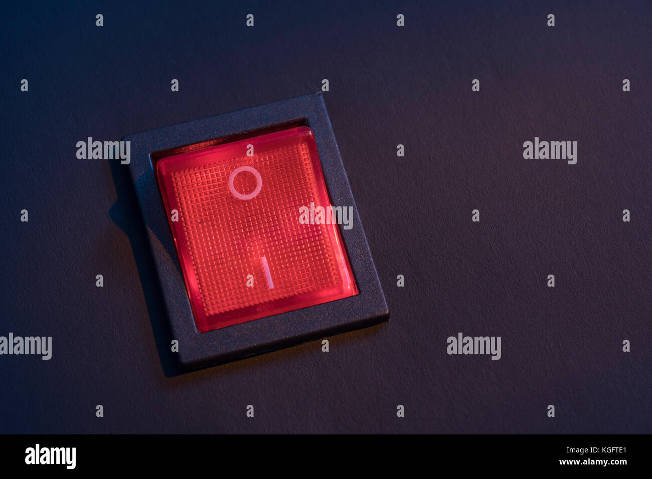 Illuminated red electrical switch on black background - potential ...