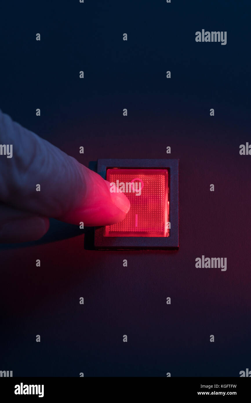 Finger hovering over illuminated red electrical switch - potential ...