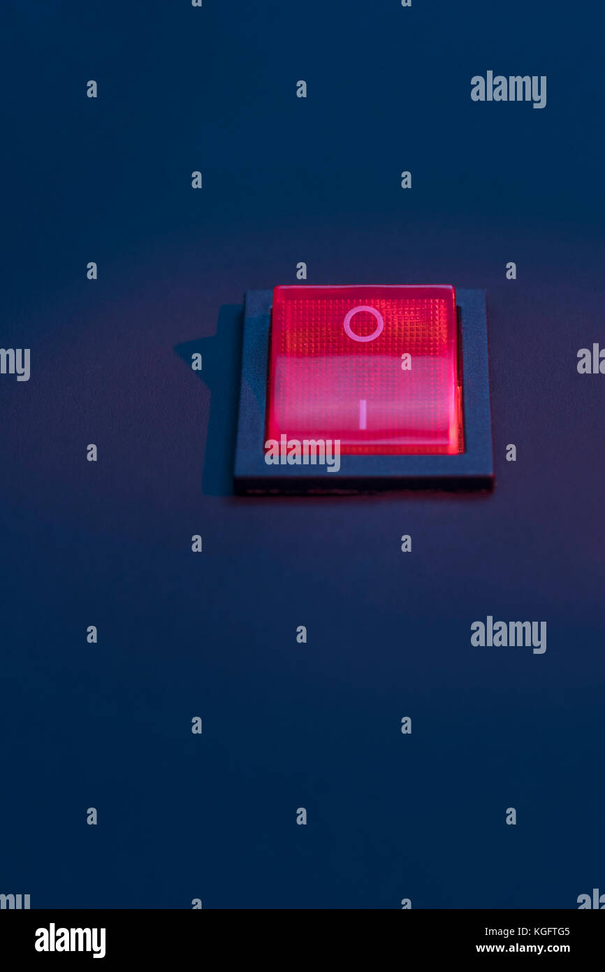 Illuminated red electrical switch on black background - potential ...