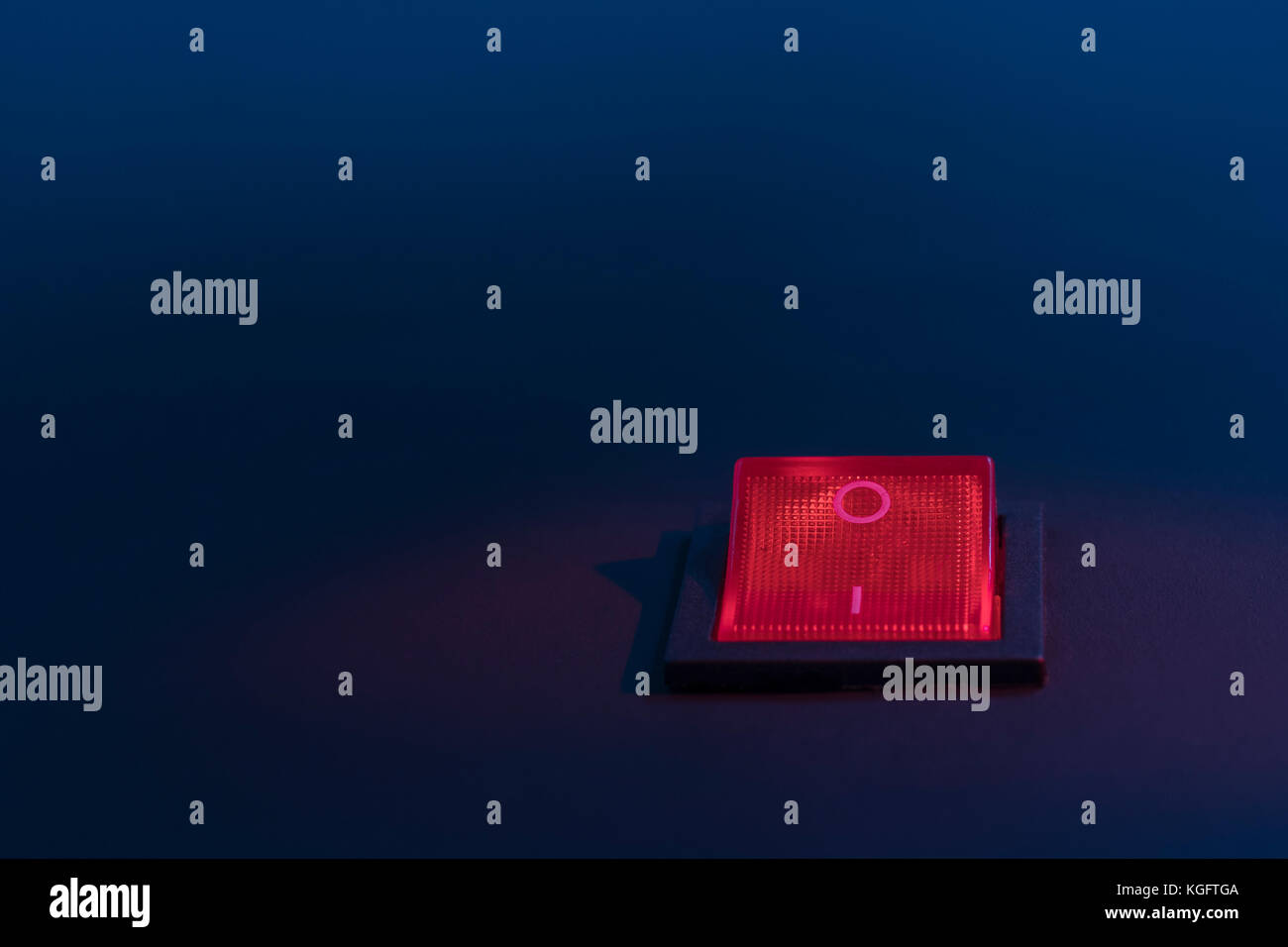 Illuminated red electrical switch on black background - potential ...